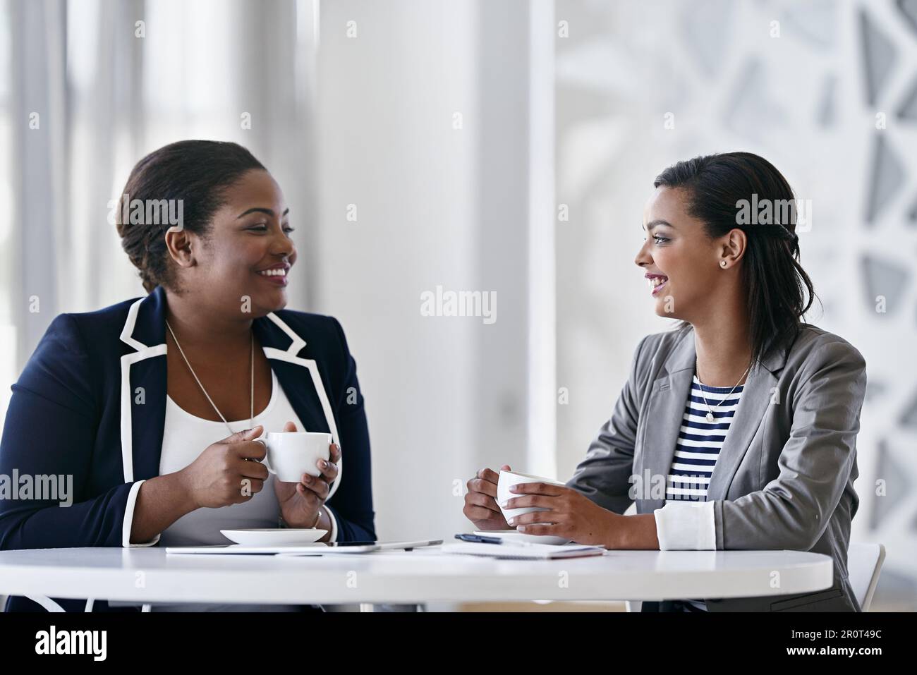 Getting work done with a smile. two coworkers talking together while ...