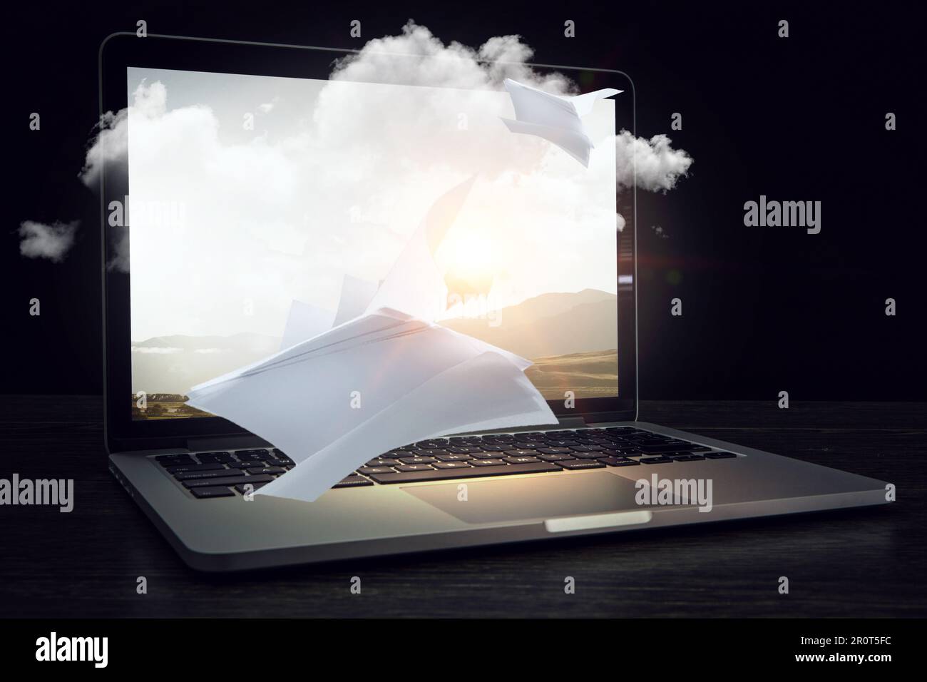 Laptop with lit screen and flying paper Stock Photo - Alamy
