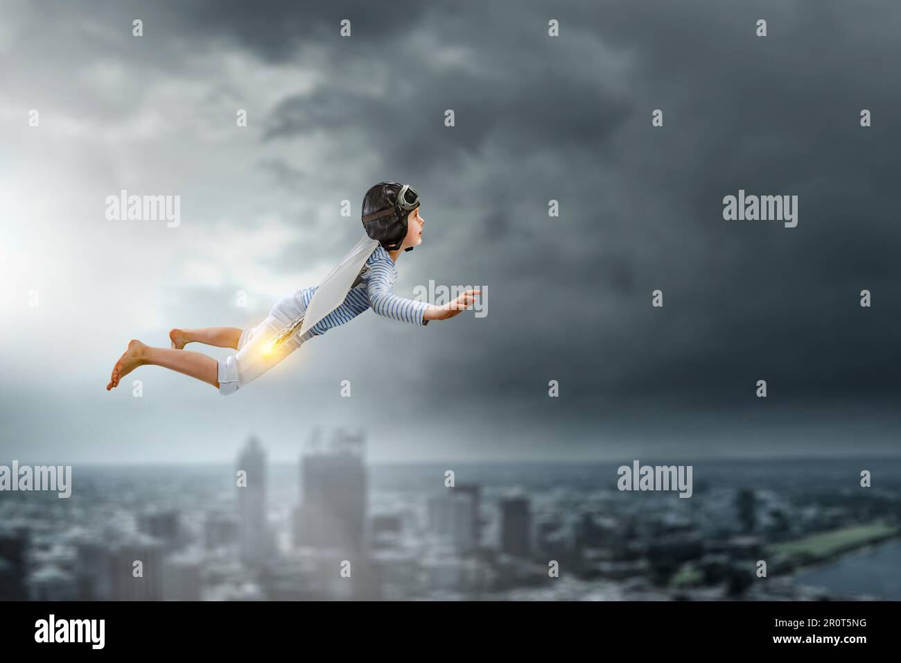 Happy little boy flying wearing helmet Stock Photo - Alamy