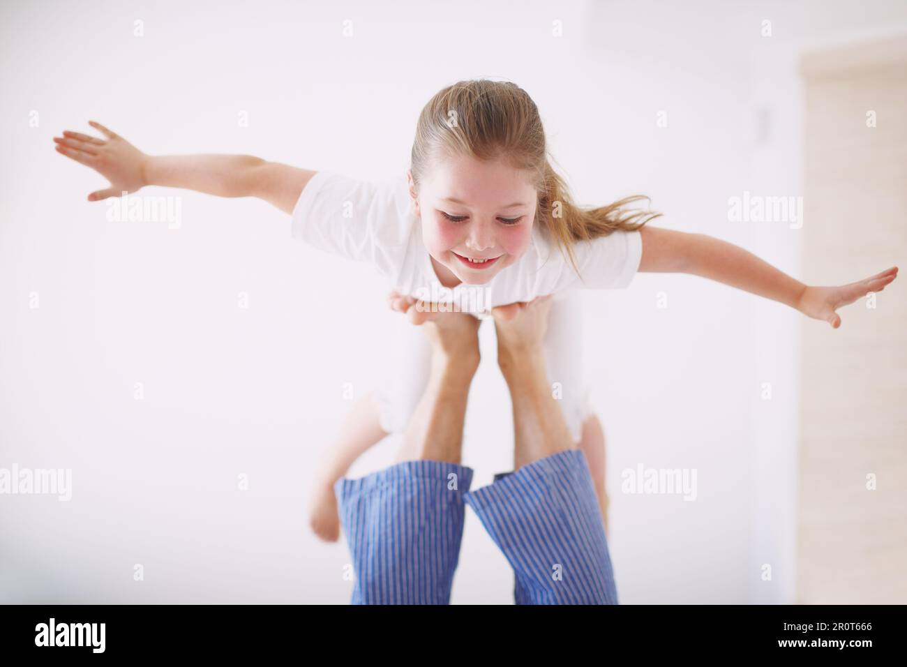 Look I can fly. A young girl propped up on her fathers feet with her ...