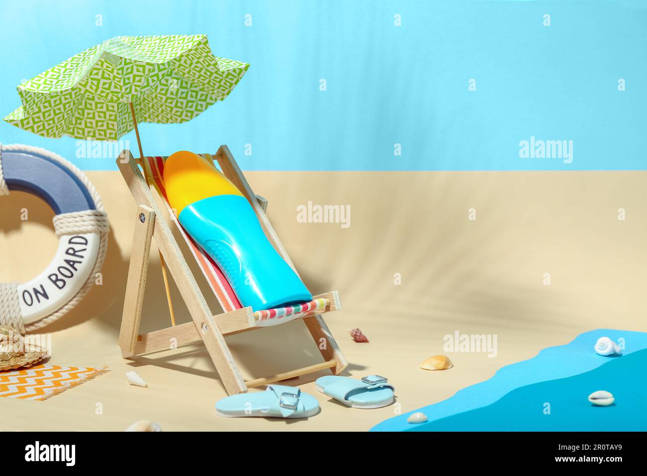 Creative composition with miniature deckchair, umbrella and sunscreen ...