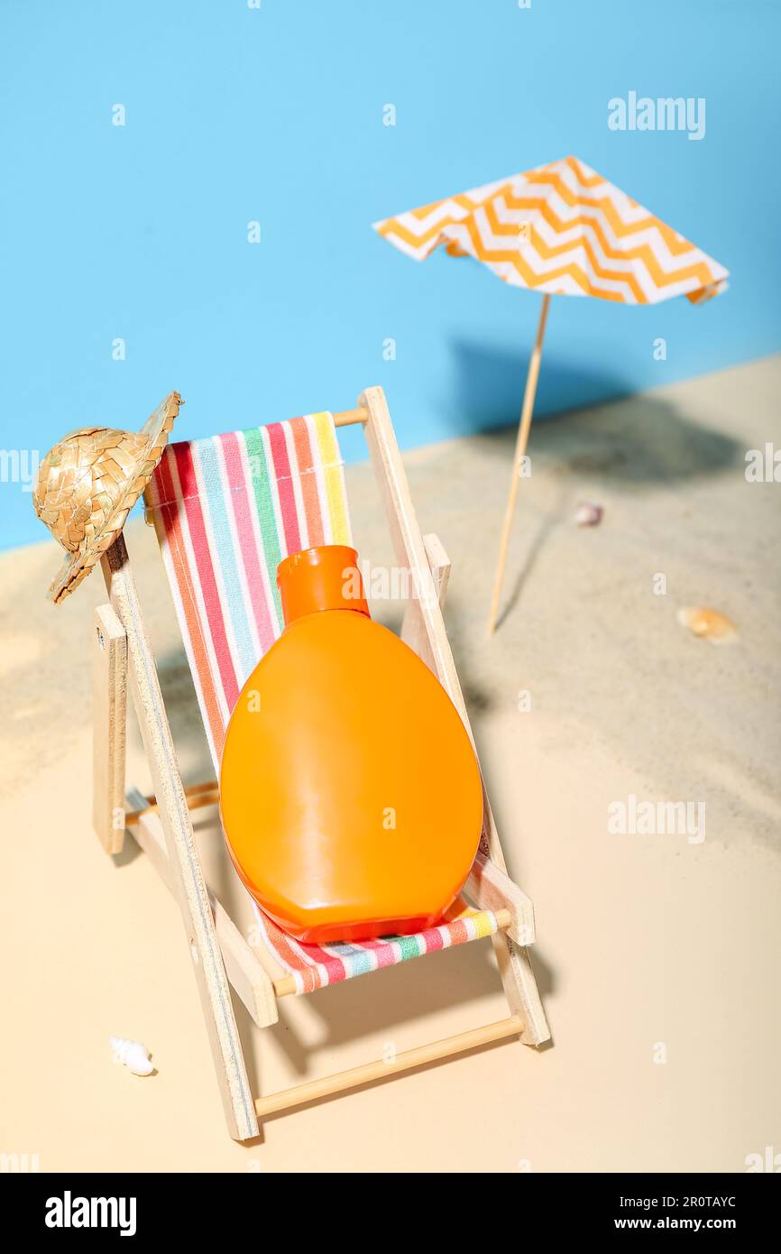 Creative composition with miniature deckchair, umbrella and sunscreen ...
