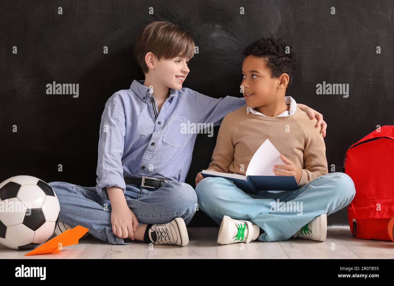 Little boys reading book near blackboard. Children's Day celebration ...