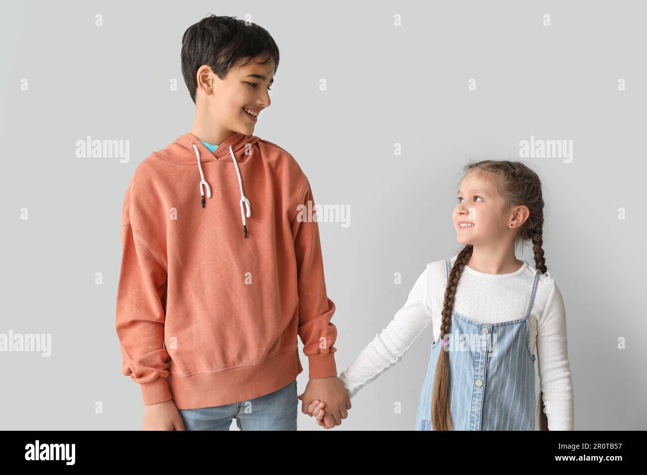 Little children holding hands on light background Stock Photo - Alamy
