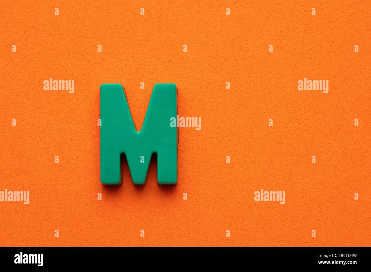 Letter M green plastic uppercase on orange foamy background Stock Photo ...