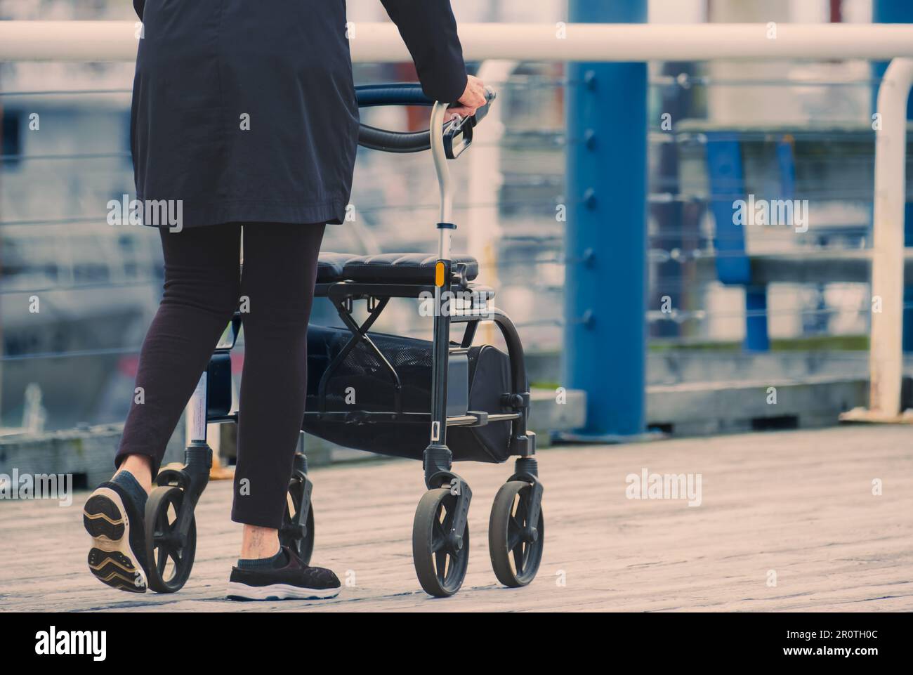 Elderly disabled woman is walking with walker. A woman holding to a ...
