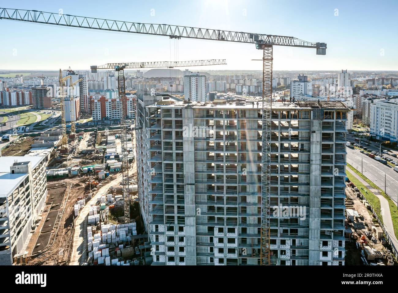 high-rise building and crane on construction site against blue sky ...