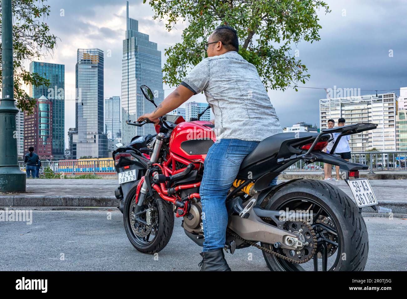 Vietnamese man riding red Ducati motorbike beside Saigon river, Ho Chi ...