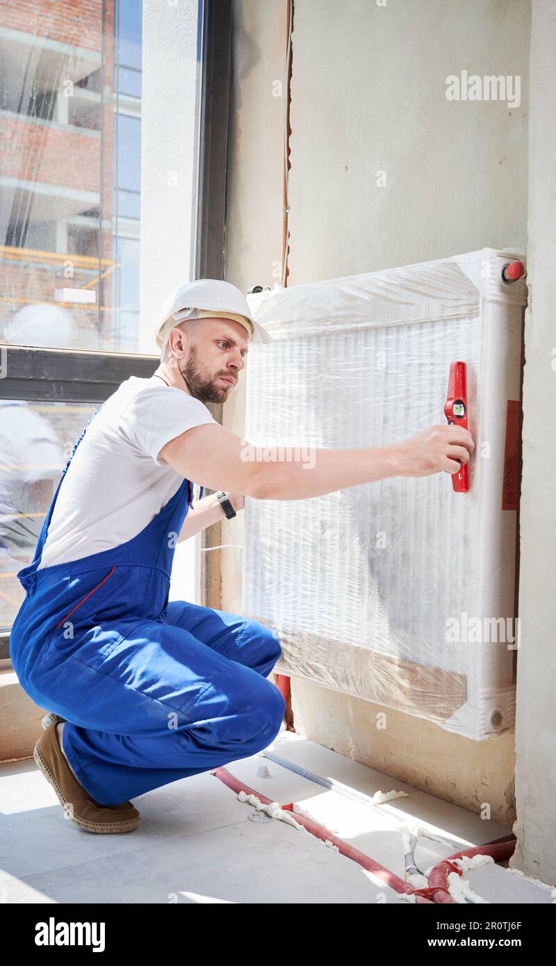 Plumber using spirit level tool while installing heating system at home ...