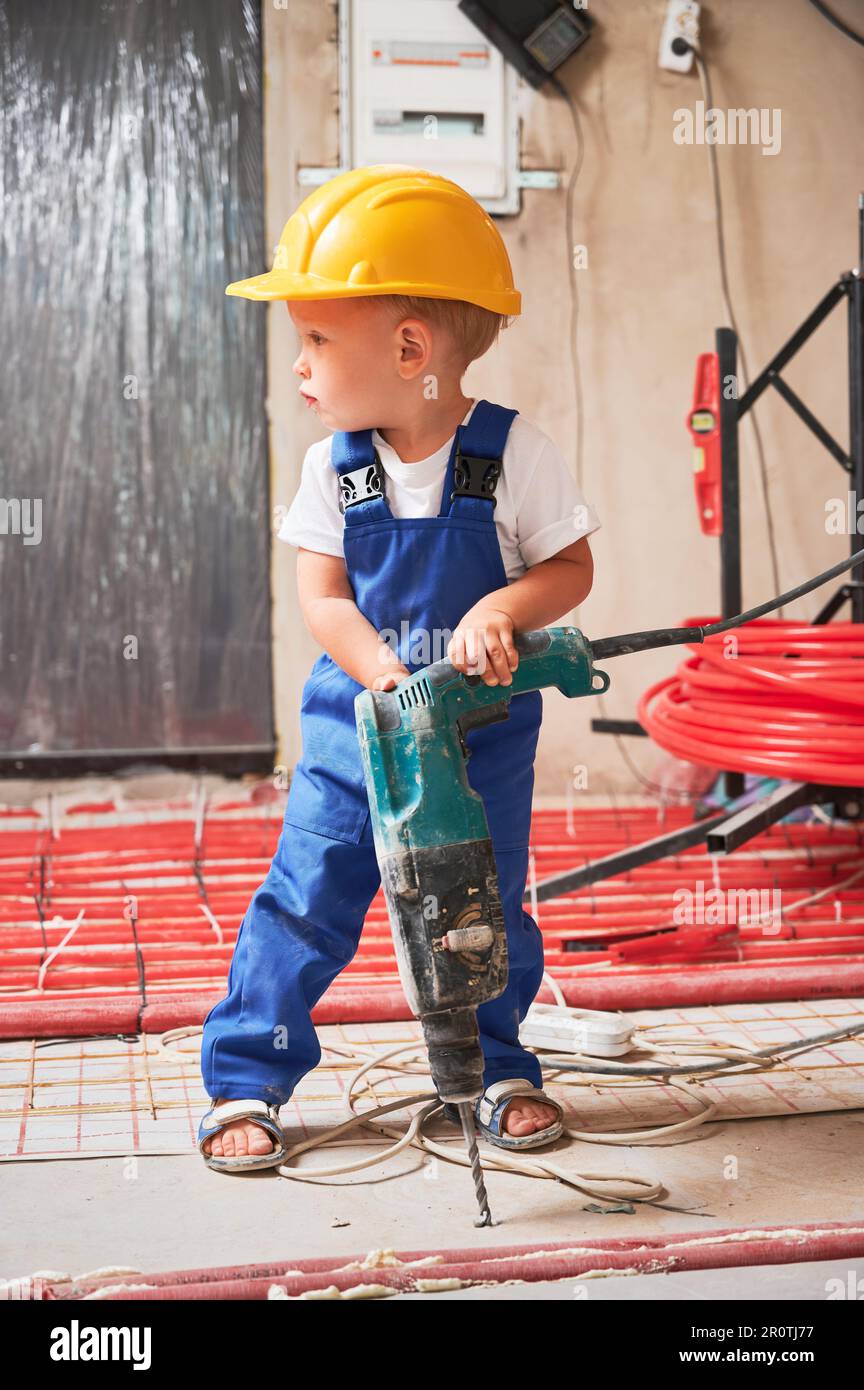 Child drilling floor with electric hammer drill at home during ...
