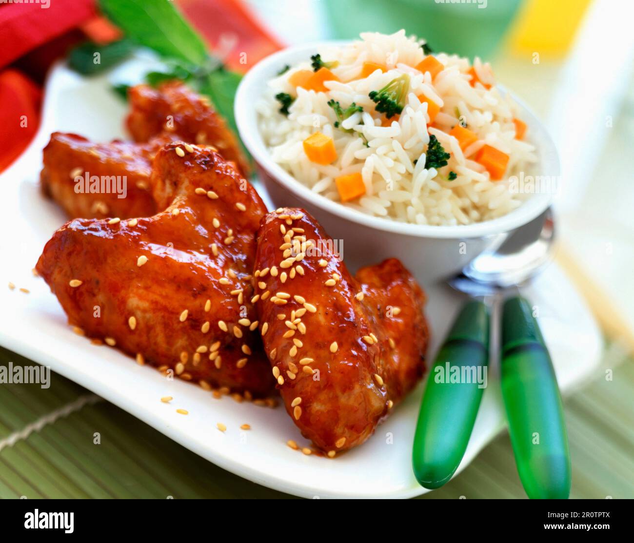 Glazed chicken wings with sesame seeds and bowl of rice Stock Photo - Alamy