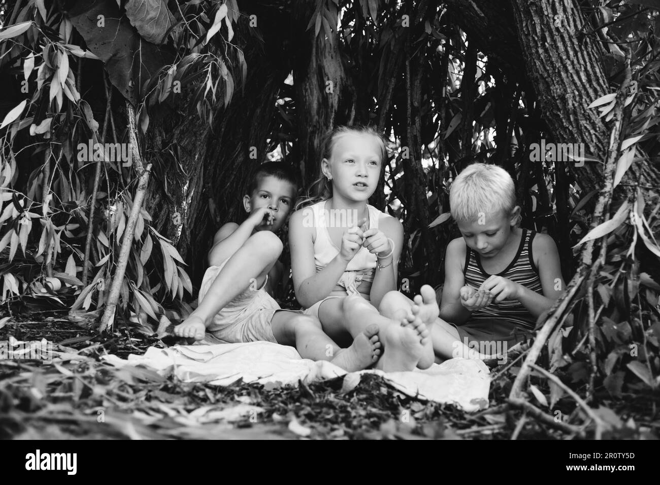 Three children play in a hut which they themselves have built from ...