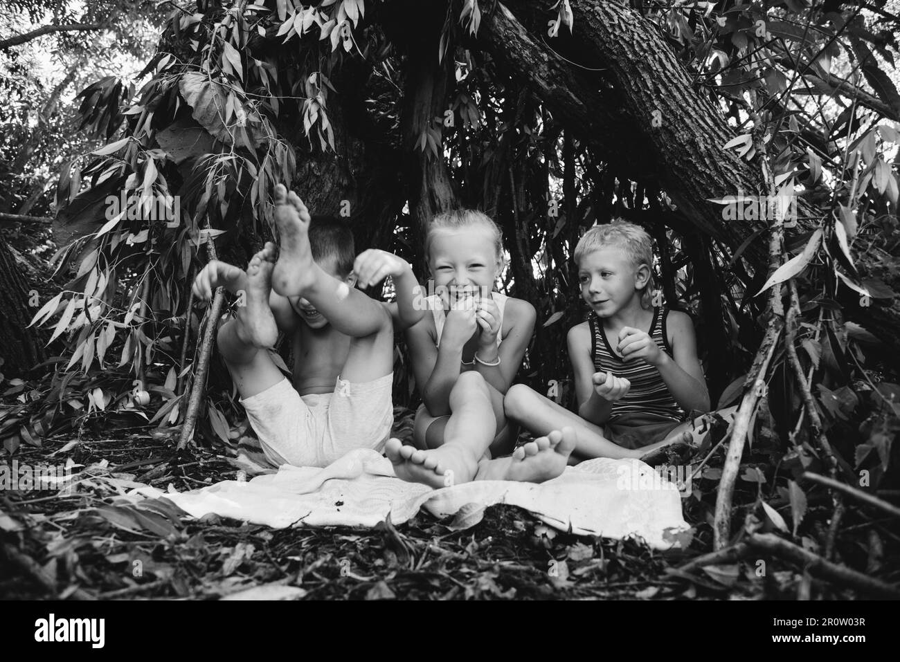 Three children play in a hut which they themselves have built from ...