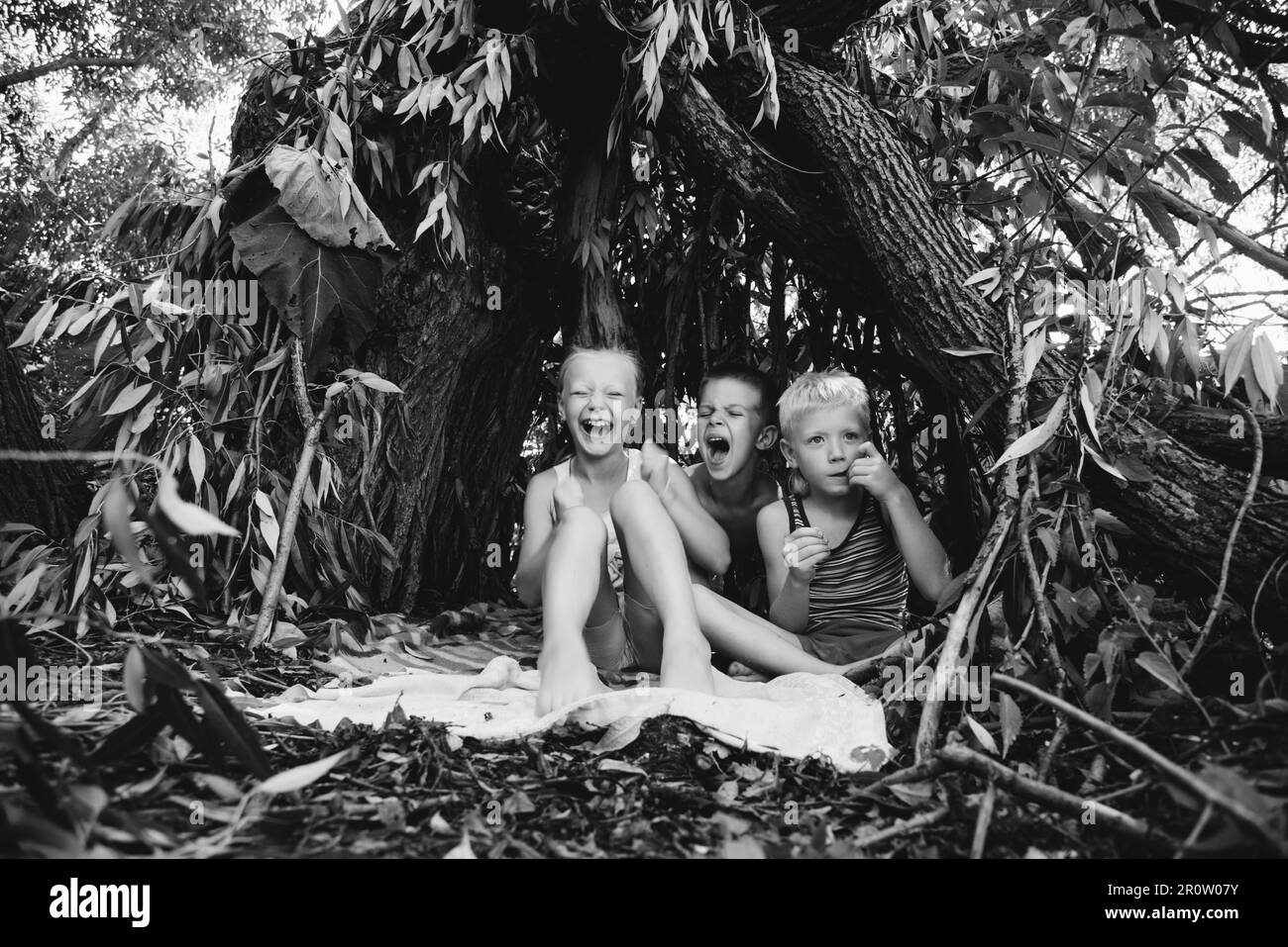 Three children play in a hut which they themselves have built from ...