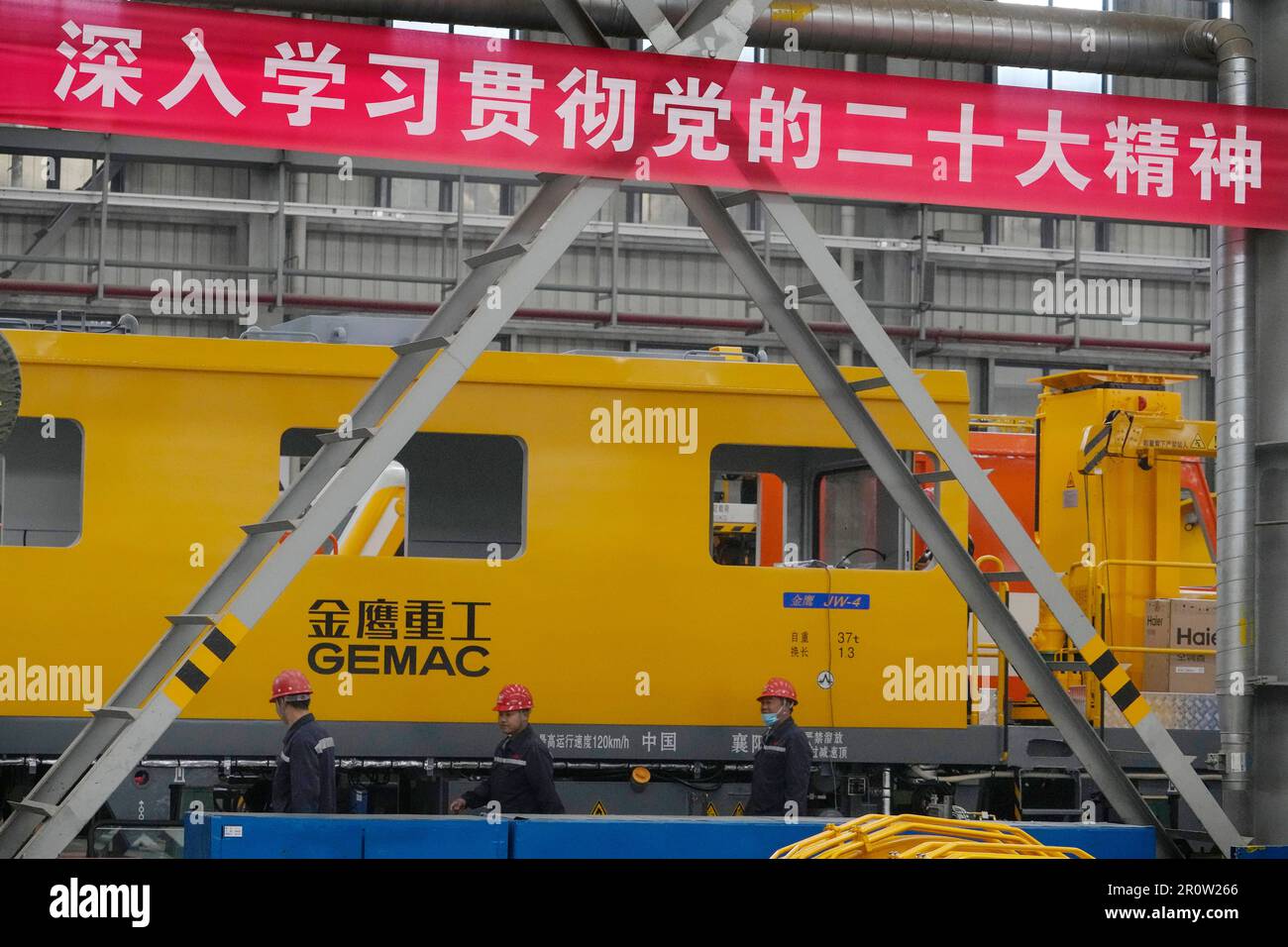 Workers walk by a cargo train compartment displaying a government propaganda banner at the GEMAC ...