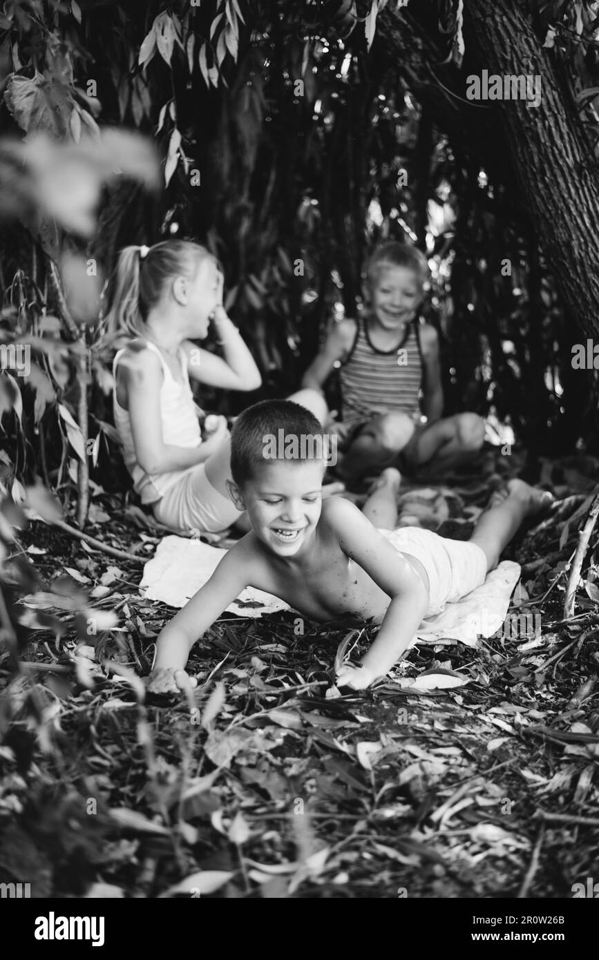 Three children play in a hut which they themselves have built from ...
