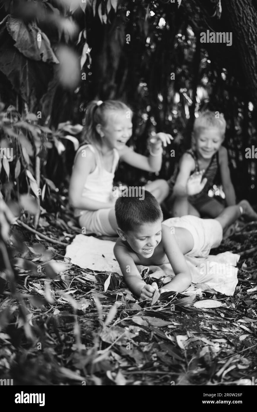 Three children play in a hut which they themselves have built from ...