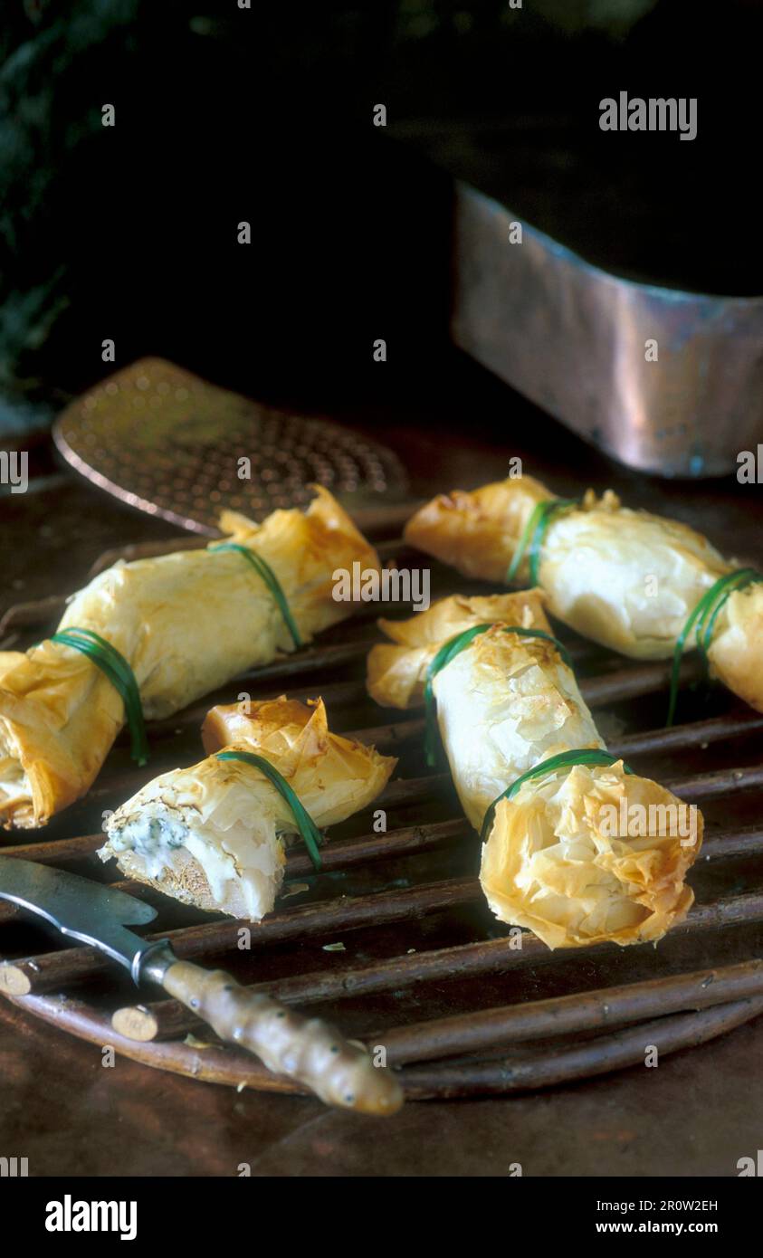 Mini pastry rolls filled with goat's cheese and peats tied with chives ...