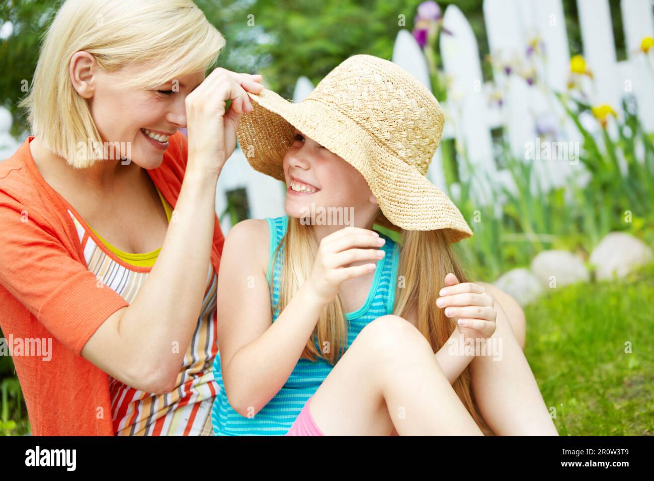 Peek-a-boo. Cute litte girl sitting on the grass outdoors with her mom ...