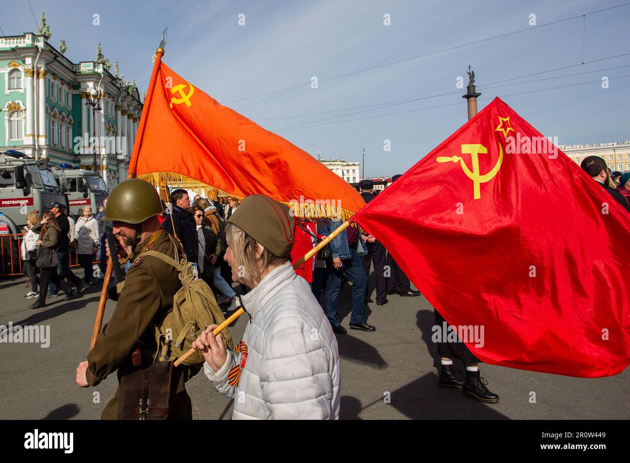 A man and a woman with the flags of the Soviet Union walk past Palace ...