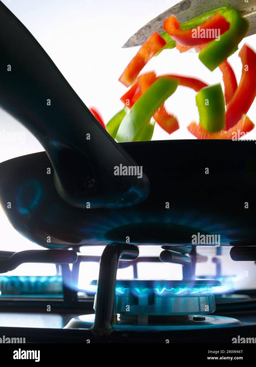 Cooking peppers in a frying pan on a gas cooker Stock Photo - Alamy