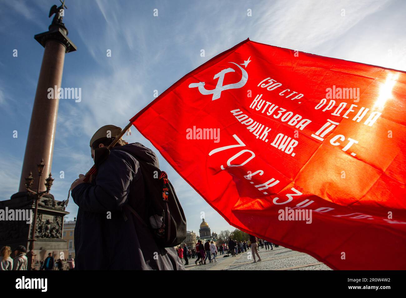 A woman holds a red flag of the Soviet Union against the backdrop of ...