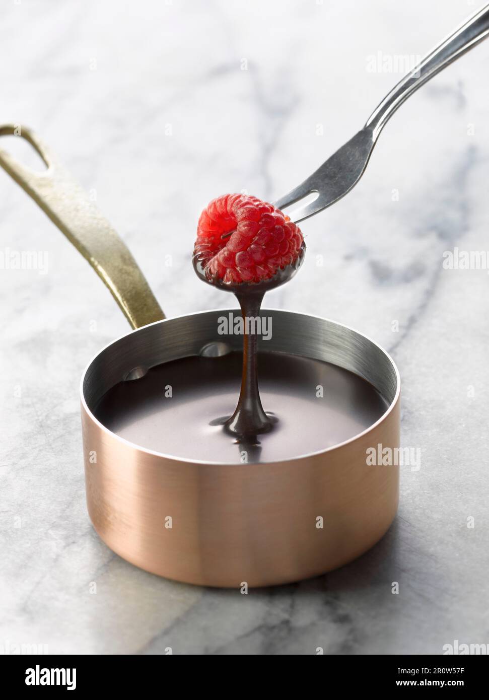 Dipping a raspberry into a saucepan of melted chocolate Stock Photo - Alamy