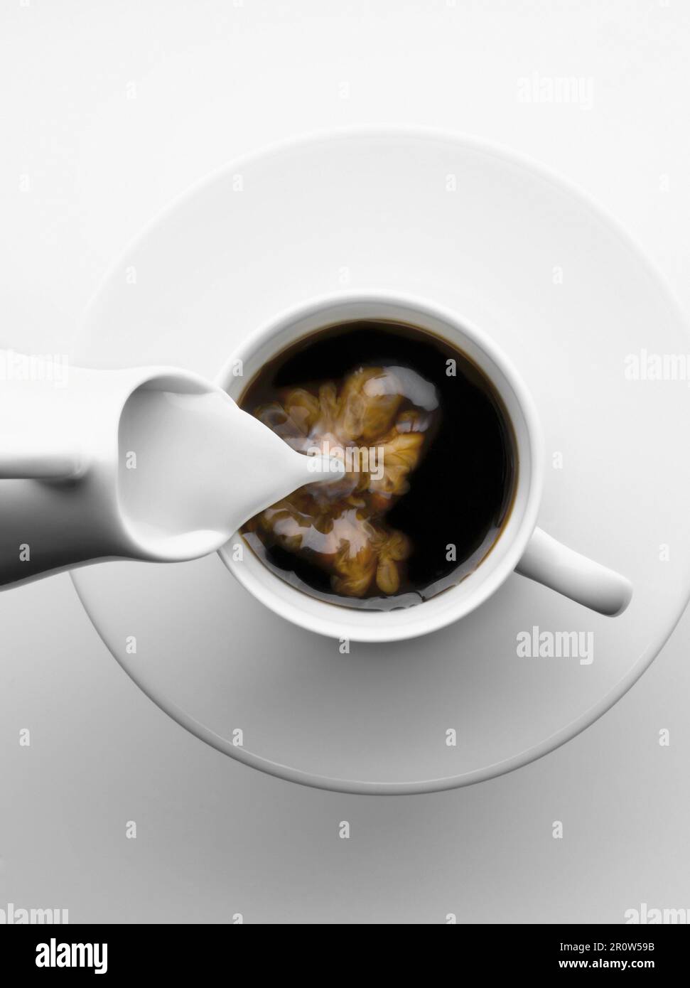Adding milk to a cup of coffee Stock Photo - Alamy