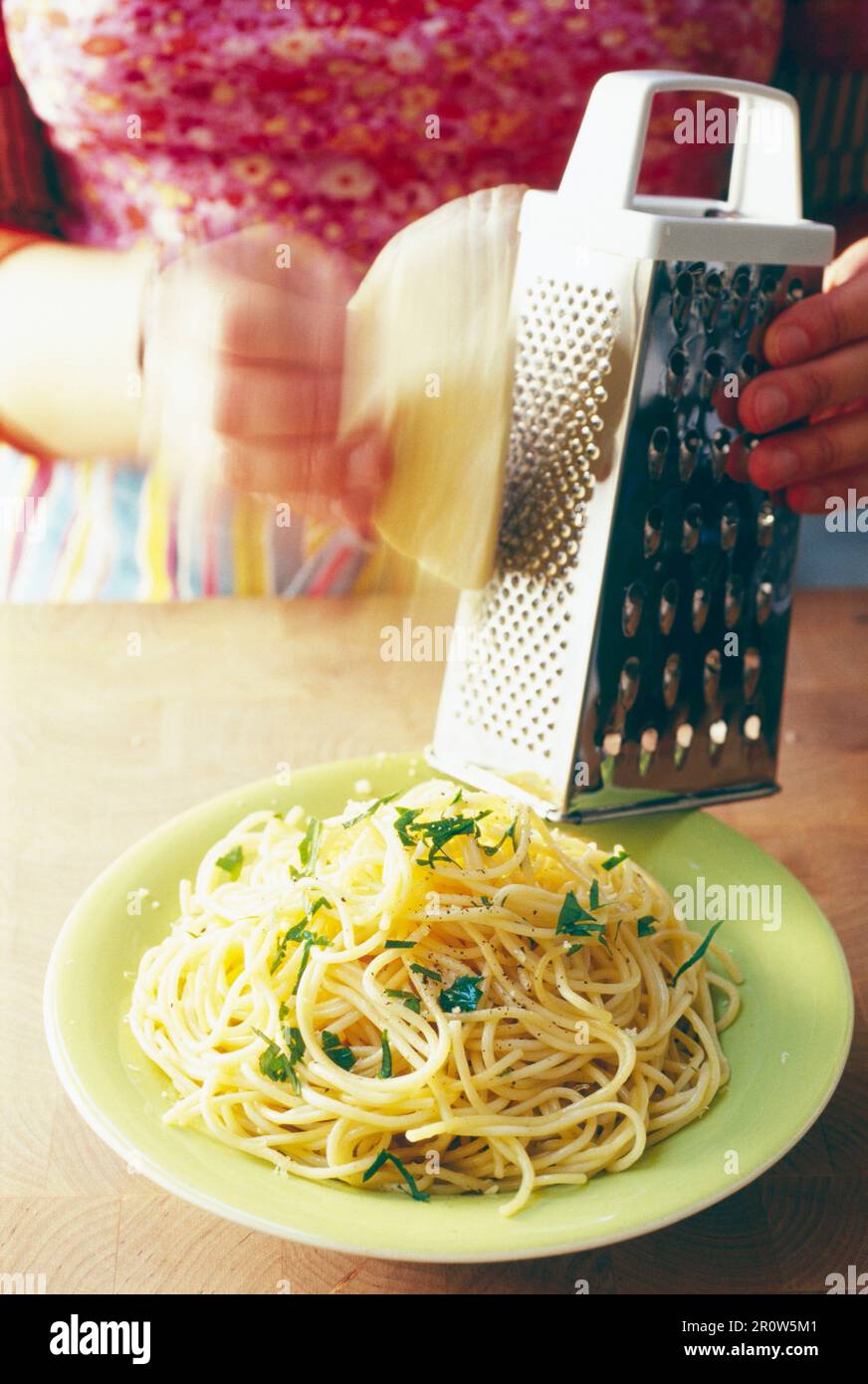 Grating cheese on a plate of spaghetti Stock Photo - Alamy