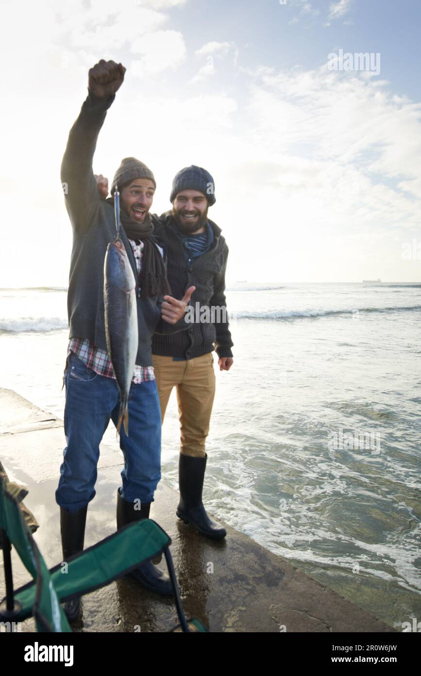 My biggest catch yet. two young men fishing at the ocean Stock Photo ...