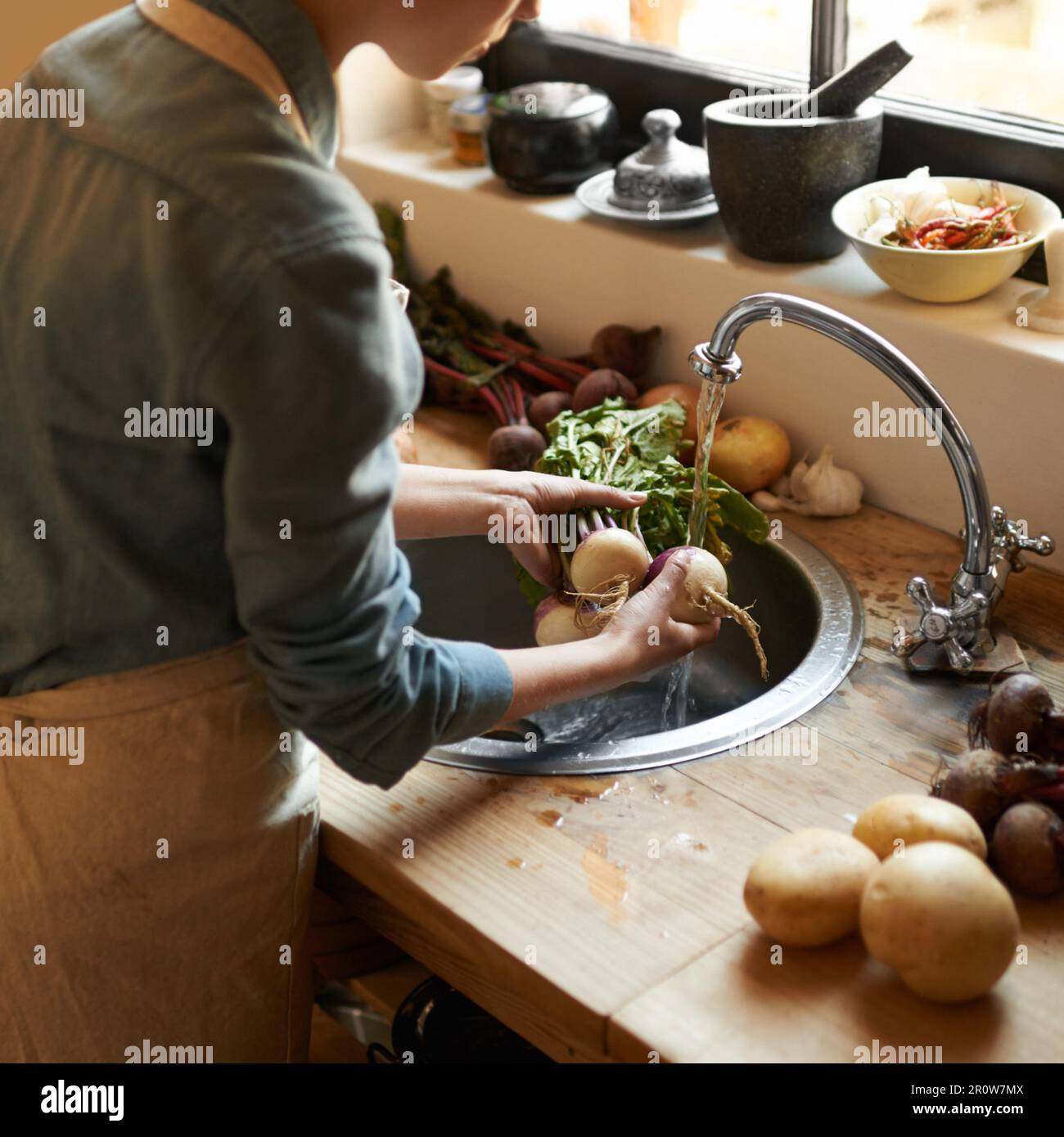 Washing them off before its time to cook. a woman washing vegetables in a sink Stock Photo - Alamy