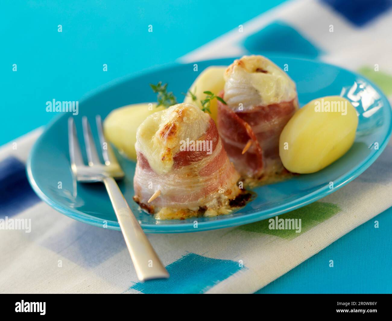 Fish fillets wrapped in bacon with steam-cooked potatoes Stock Photo ...