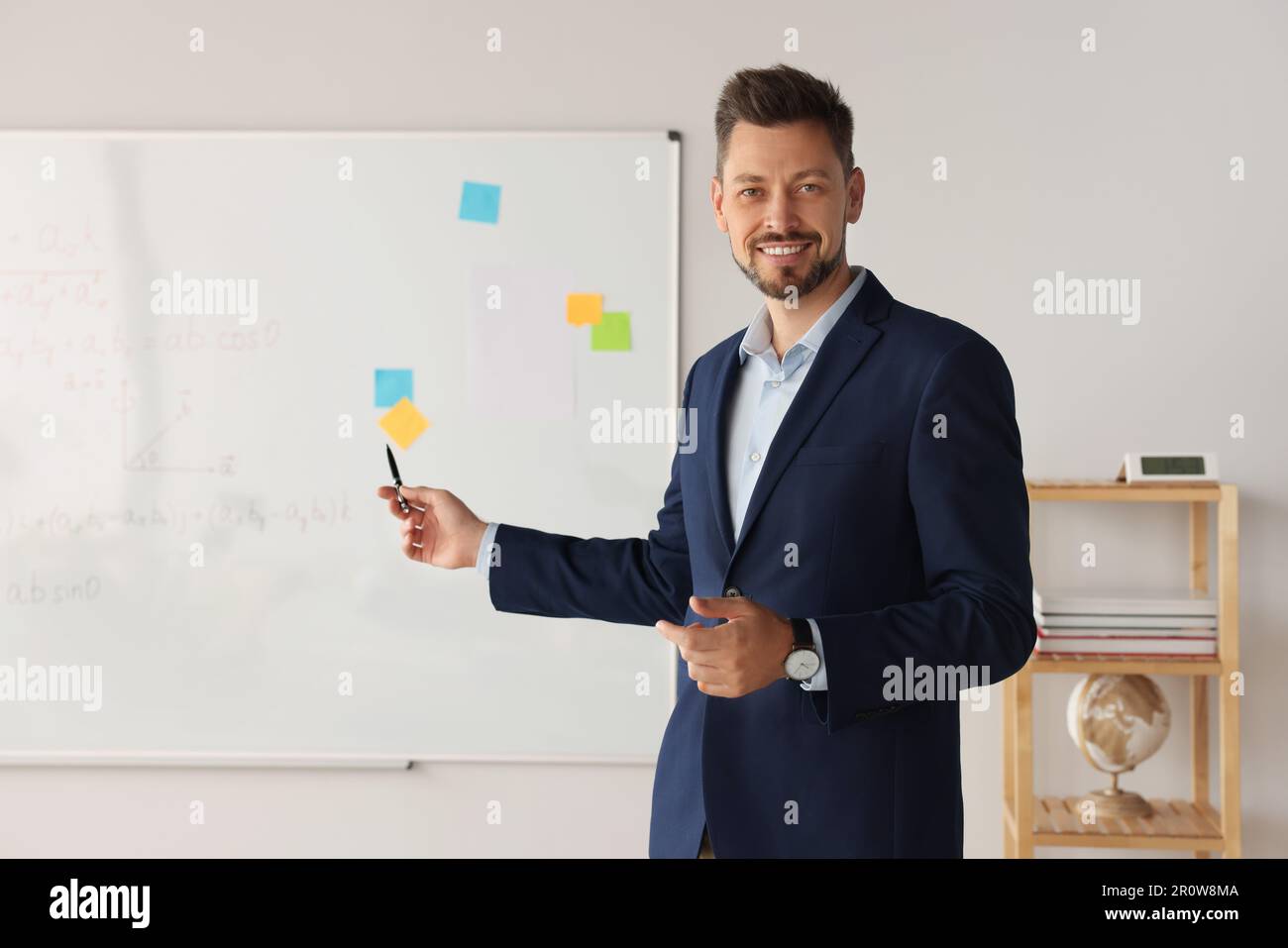 Happy teacher explaining mathematics at whiteboard in classroom Stock ...