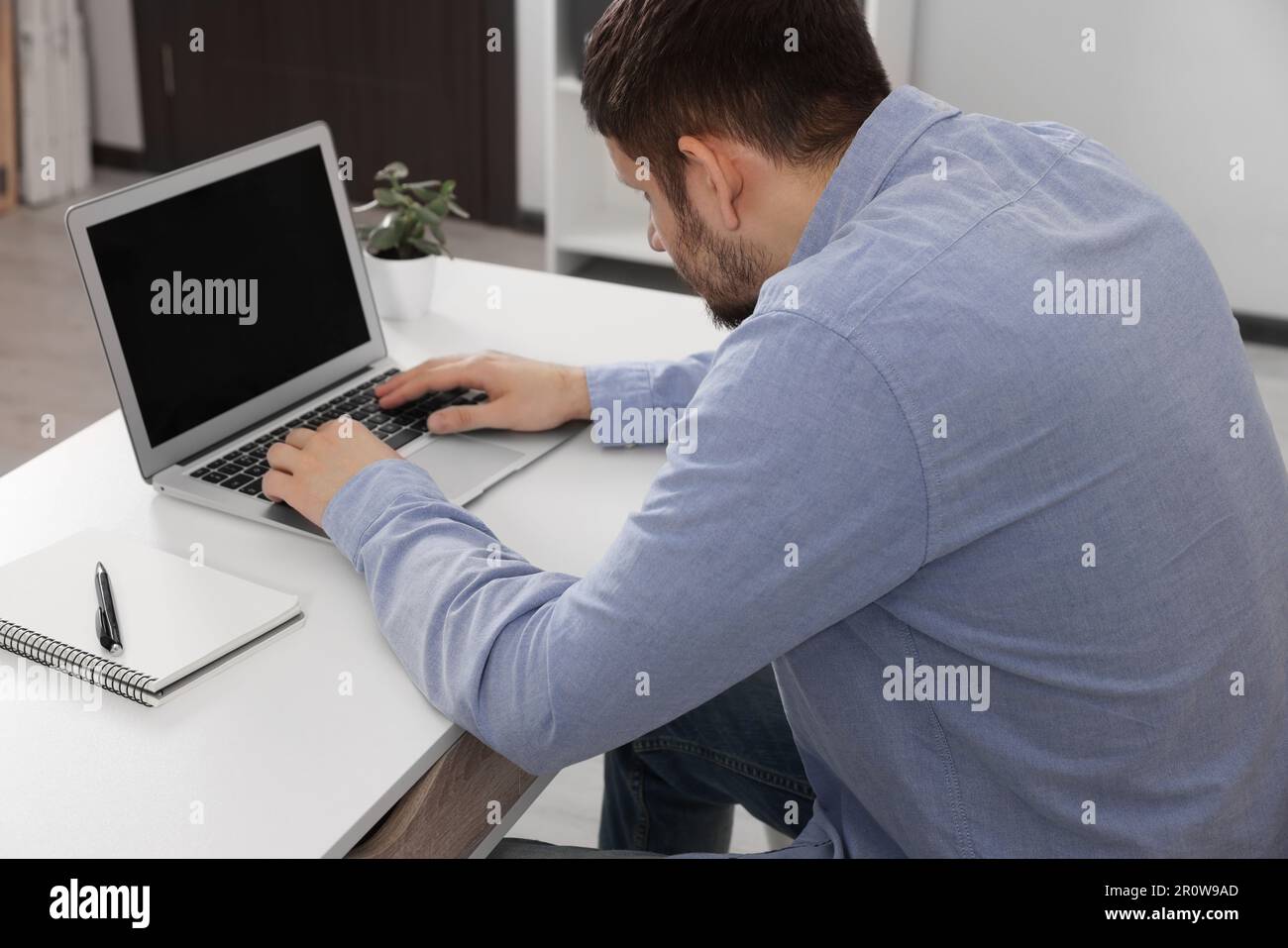 Man with poor posture working on laptop in office. Symptom of scoliosis ...