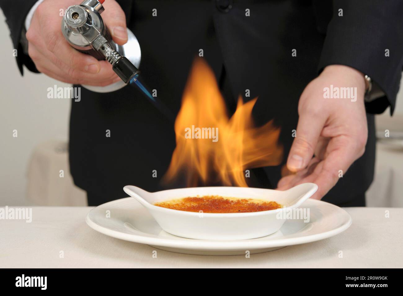Caramelizing a Crème brûlée with a blowtorch Stock Photo - Alamy