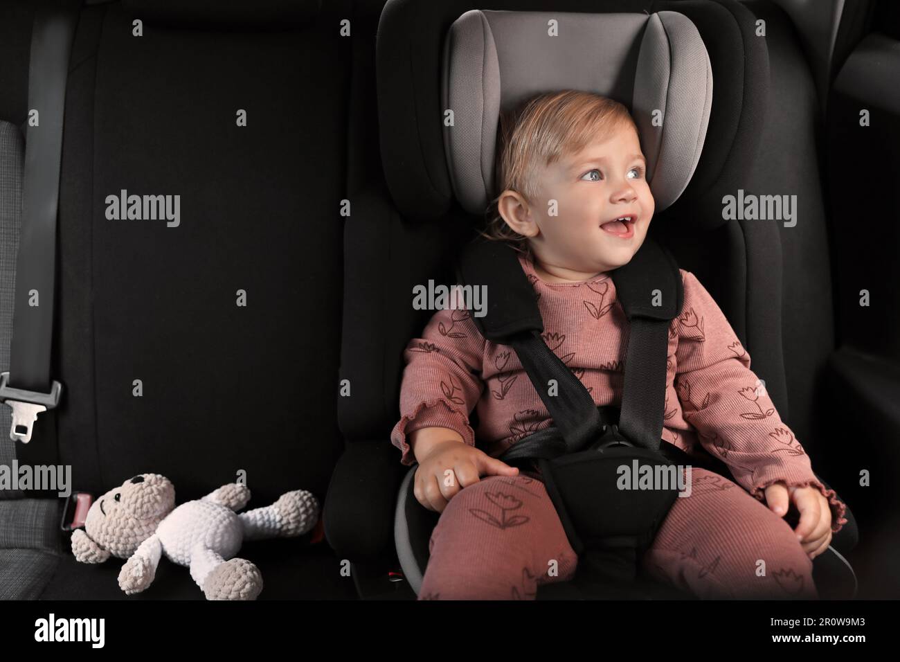 Cute little girl sitting in child safety seat inside car Stock Photo ...