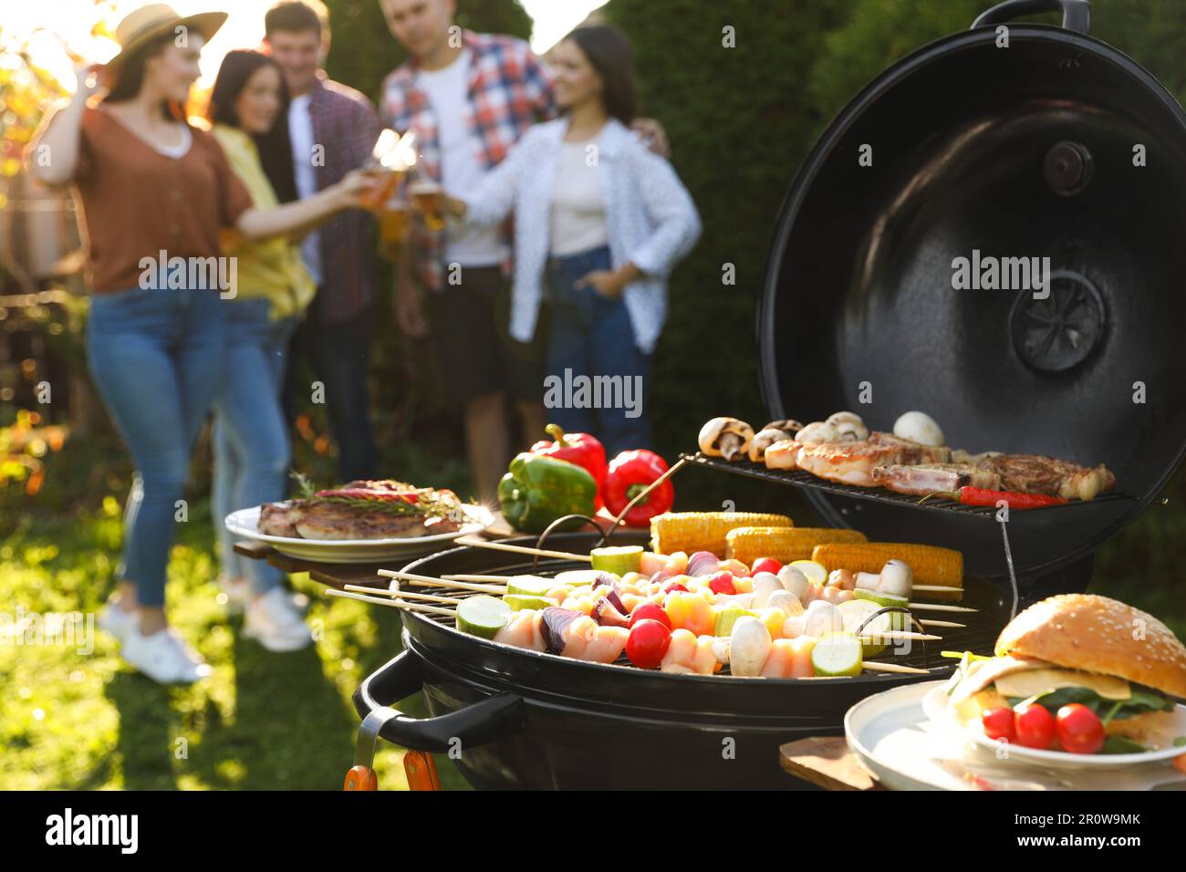 Group of friends having party outdoors. Focus on barbecue grill with ...
