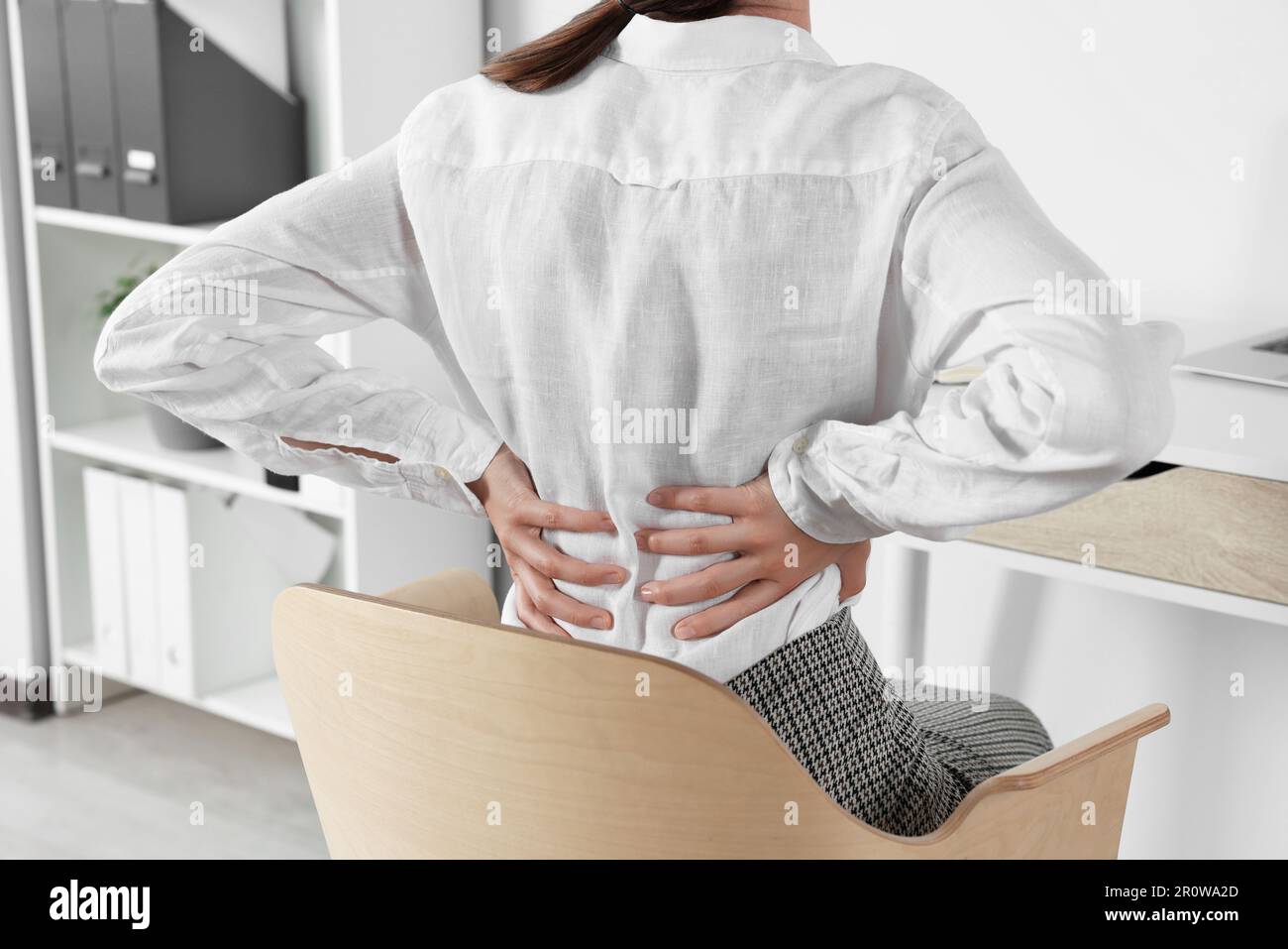 Woman suffering from back pain while sitting in office, closeup ...
