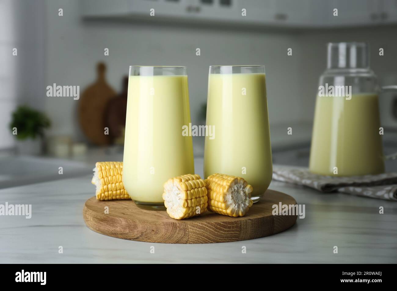 Tasty fresh corn milk in glasses and cobs on white table indoors Stock ...