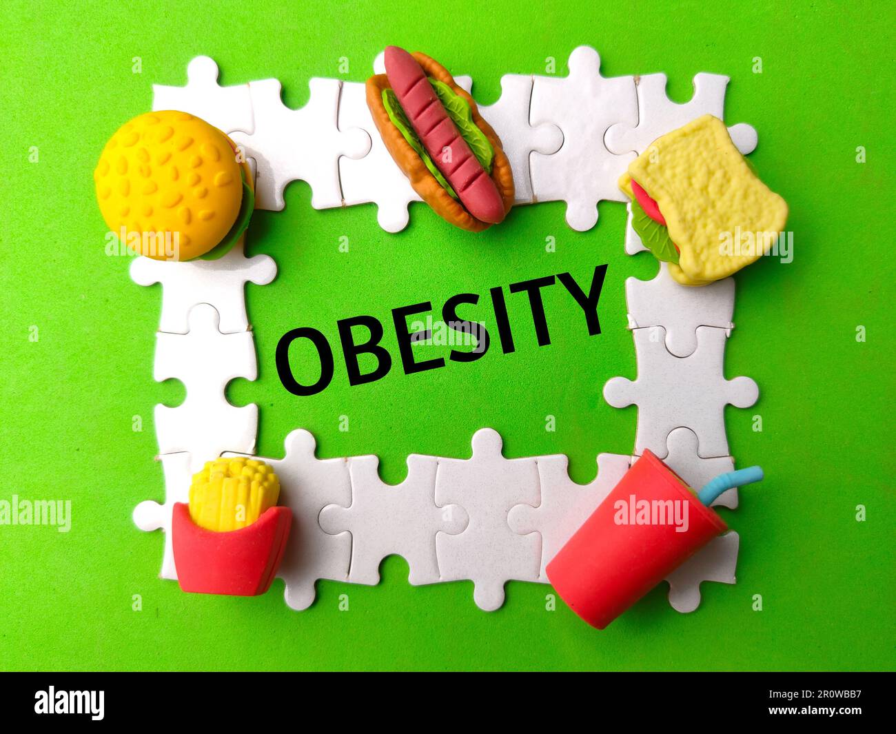 Fastfood and puzzle with the word OBESITY on green background Stock ...