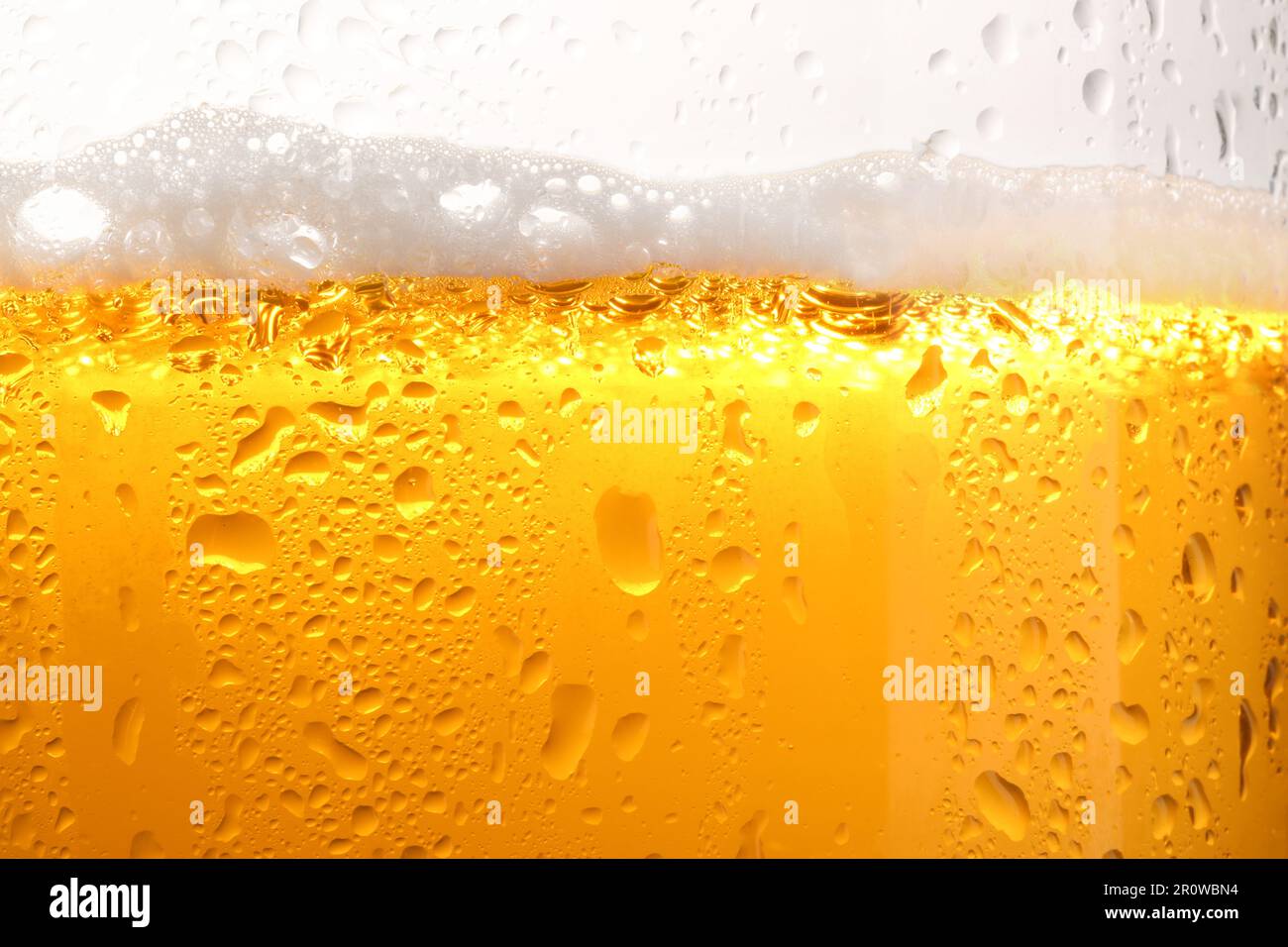 Glass of tasty cold beer with foam and condensation drops on white ...