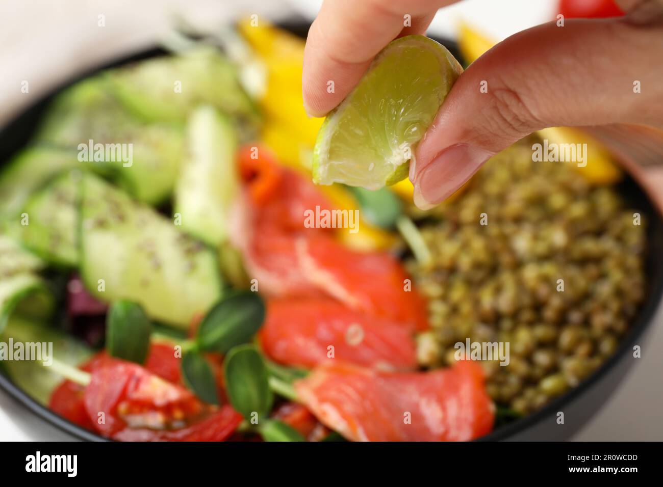 Woman adding lemon juice to salad with mung beans, closeup. Space for ...