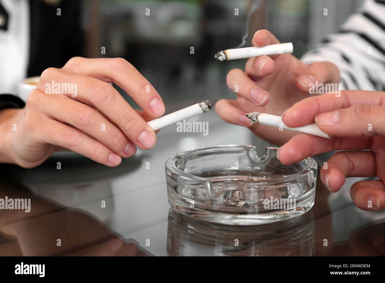 Women holding cigarette over glass ashtray at table, closeup Stock ...