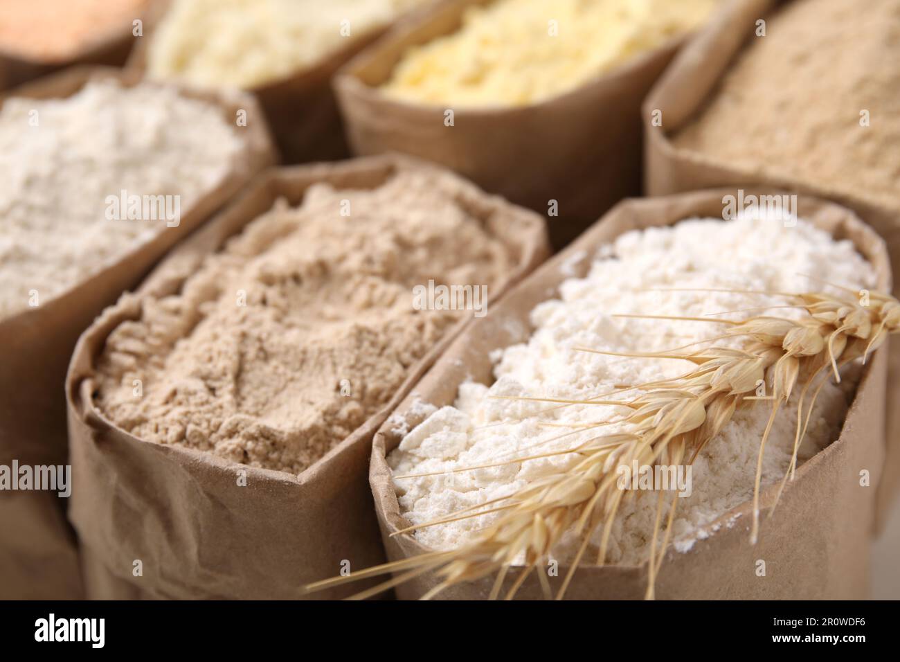 Paper sacks with different types of flour as background, closeup Stock ...