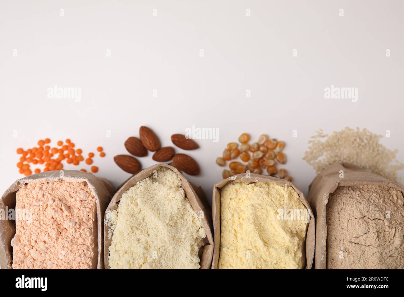 Paper bags with different types of flour on white background, top view ...