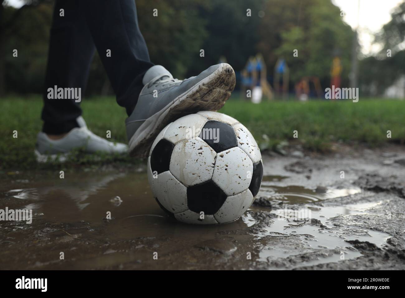 Man with dirty soccer ball in puddle outdoors, closeup Stock Photo - Alamy
