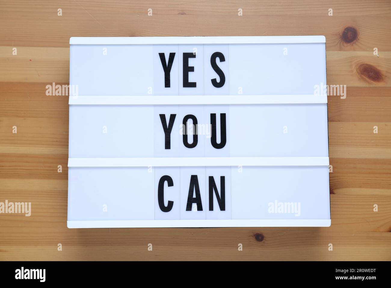 Lightbox with phrase Yes You Can on wooden table, top view ...