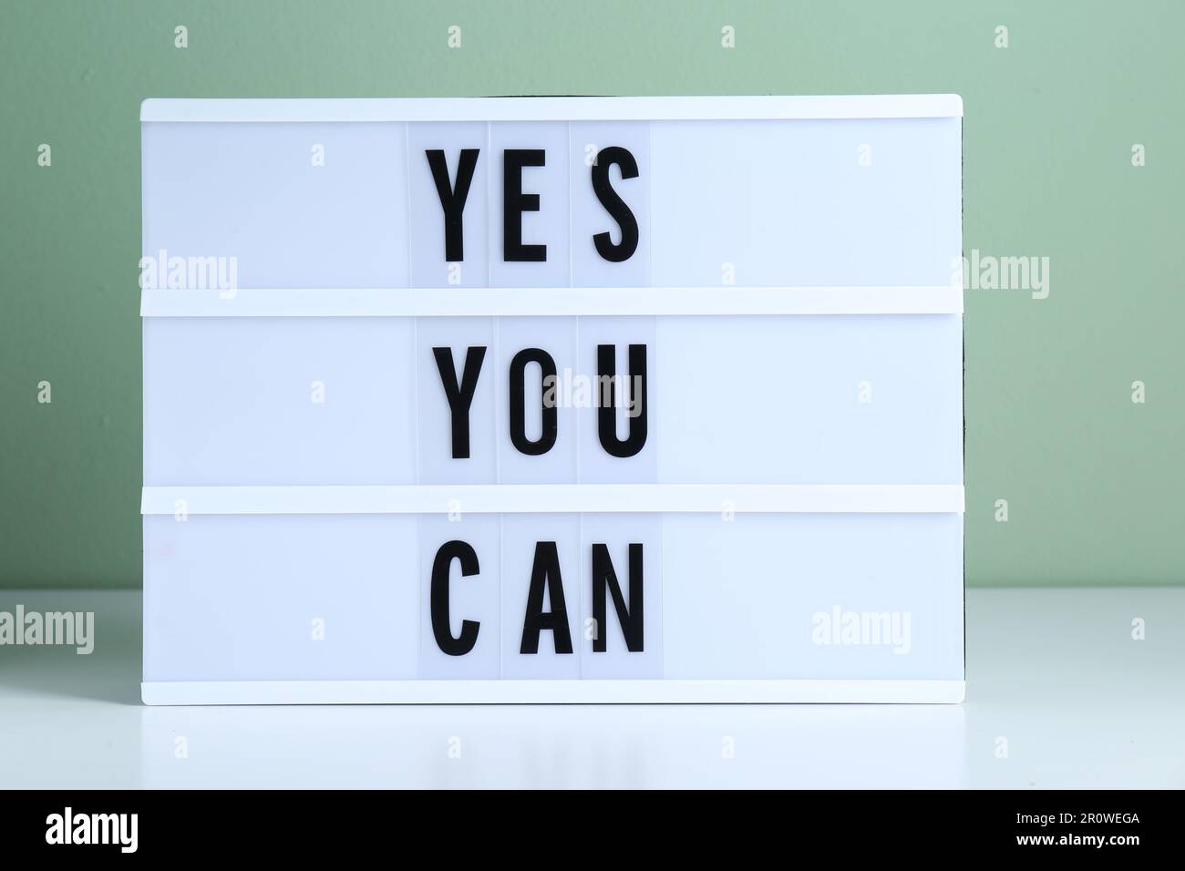 Lightbox with phrase Yes You Can on table against light green ...