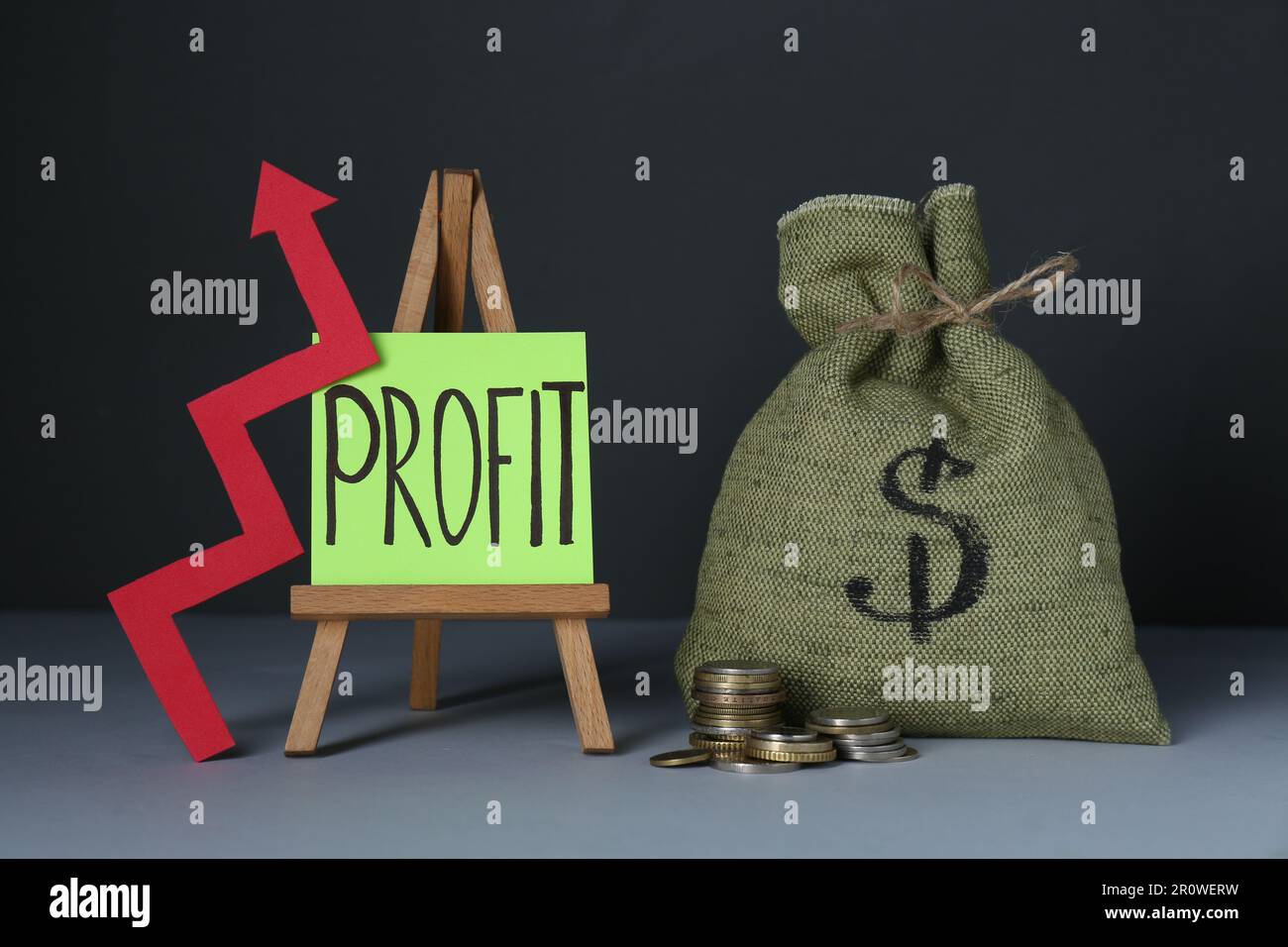 Economic profit. Money bag, arrow, coins and easel with note on grey ...