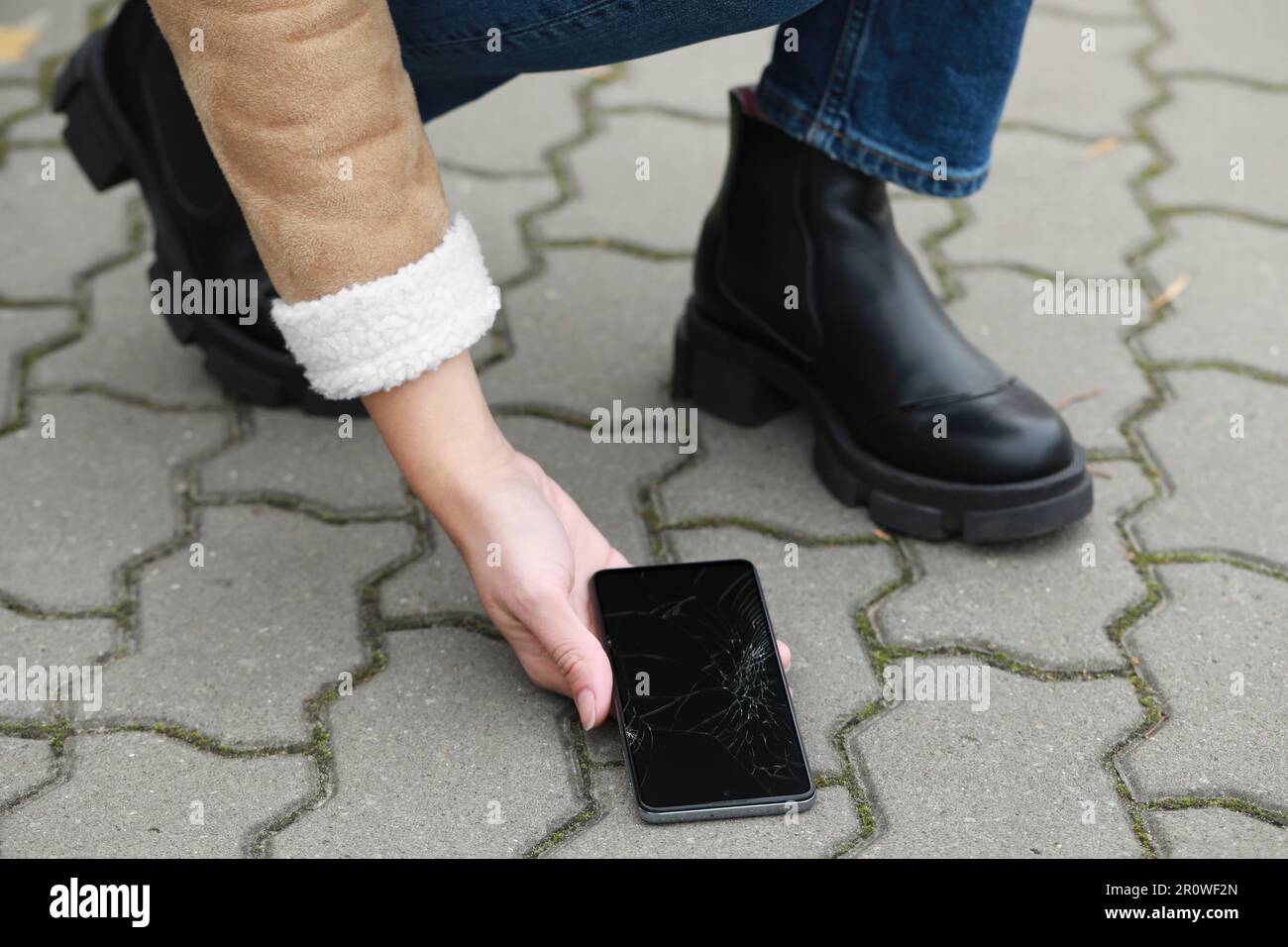 Woman taking dropped smartphone from pavement, closeup. Device ...